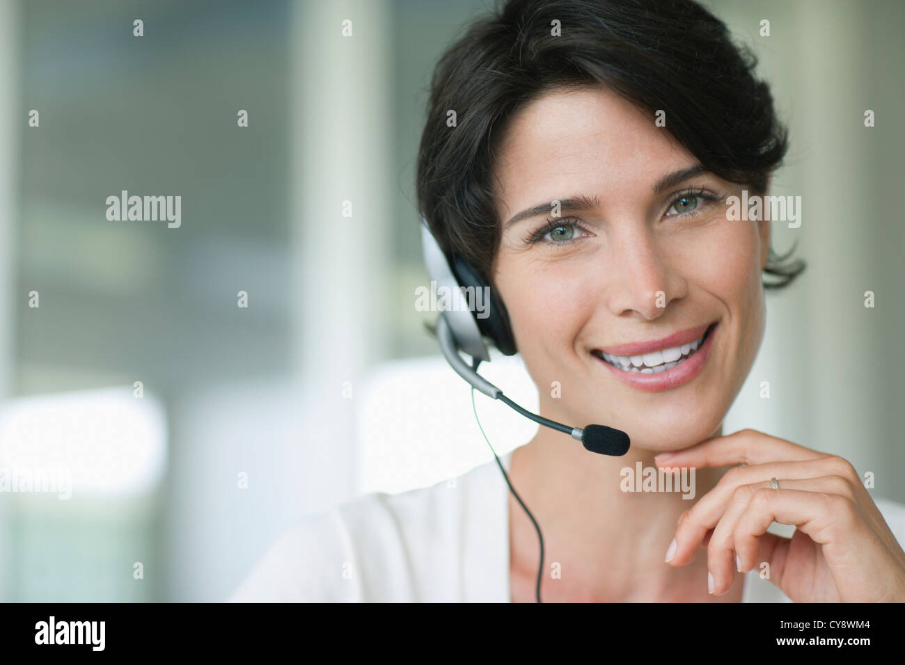 Woman using headset, smiling cheerfully Stock Photo - Alamy