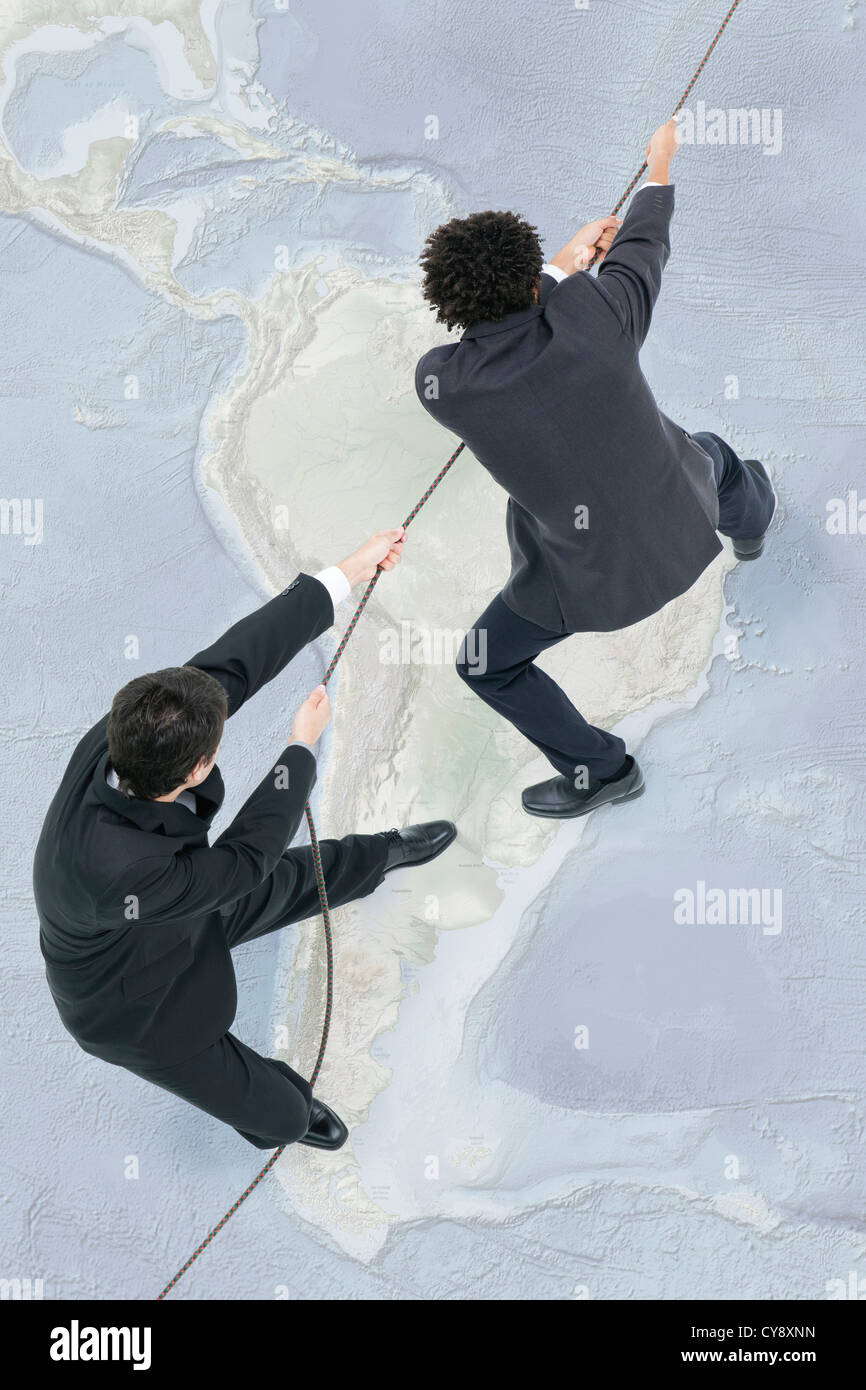 Businessmen standing on top of world map, pulling rope Stock Photo - Alamy