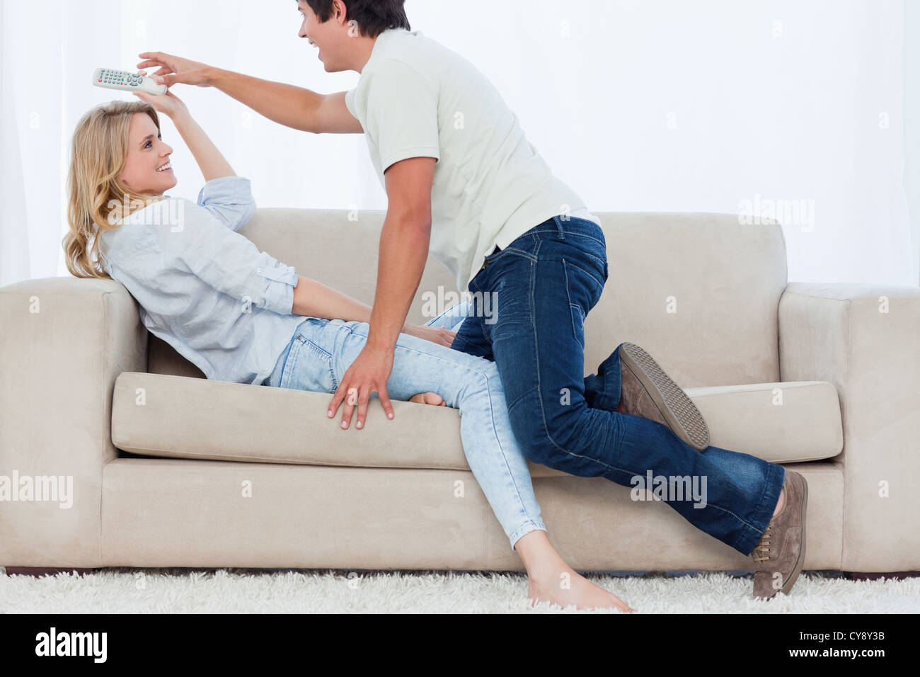 A man tries to get the television remote control off his girlfriend ...
