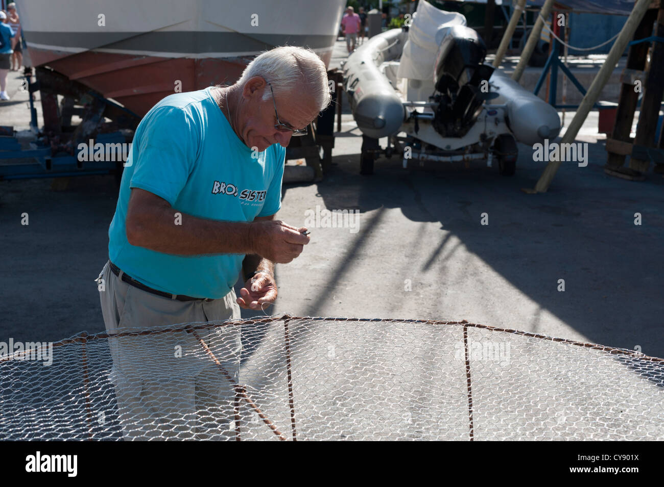 A man mending wire fishing pots on the harbour at Puerto de Mogan Gran ...