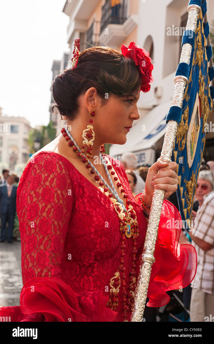 A woman follows a Religious Procession in Fuengirola. Spain. Carrying a ...