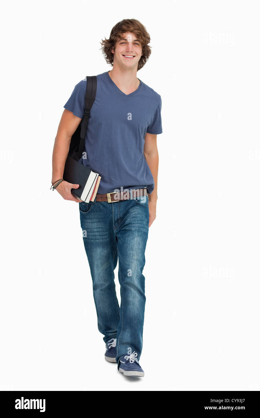 Front view of a male student walking with a backpack and books Stock ...