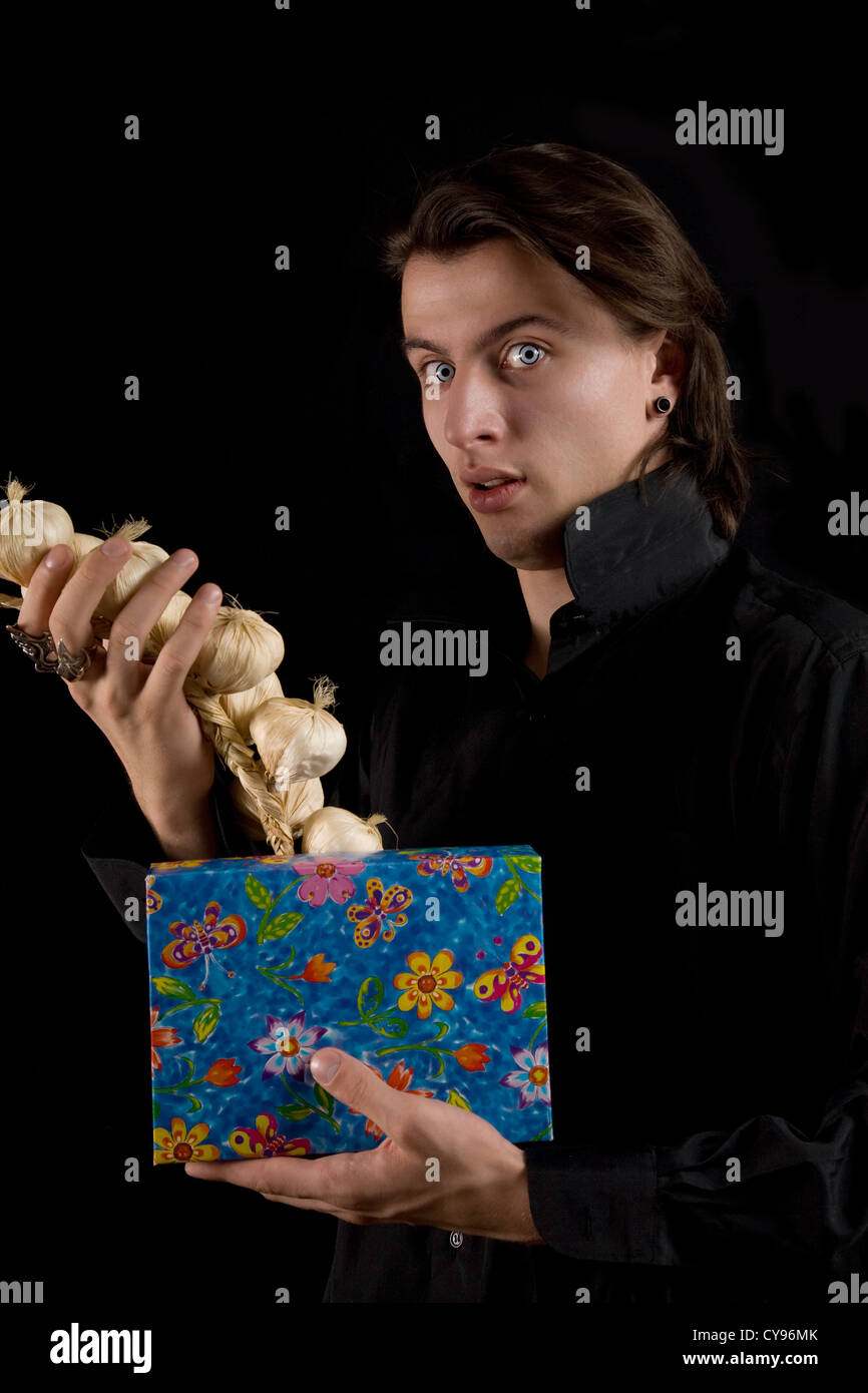 Funny vampire with gift box taking out garlic, isolated on black ...