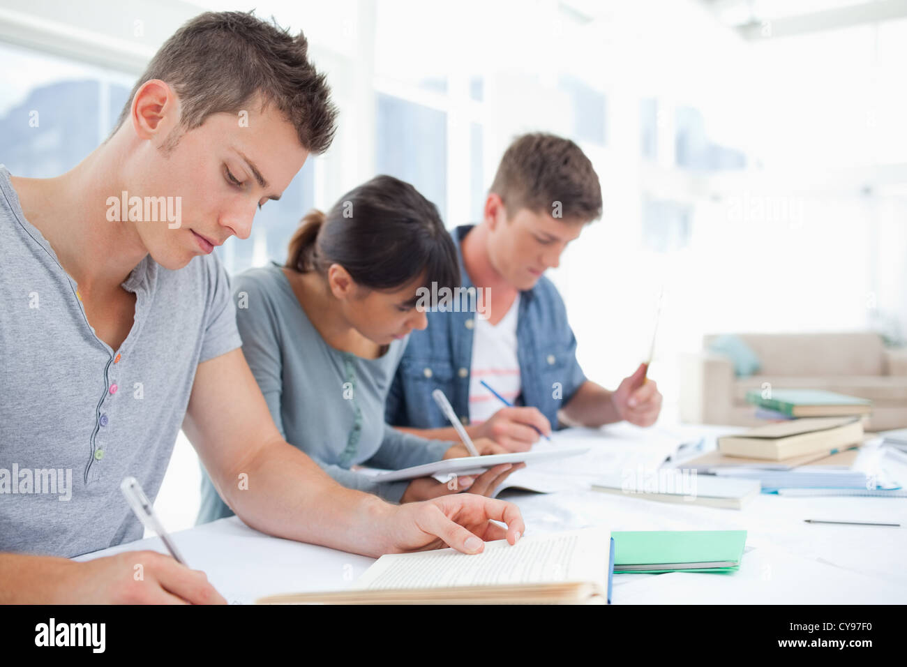 Side view of three students quietly working together Stock Photo - Alamy