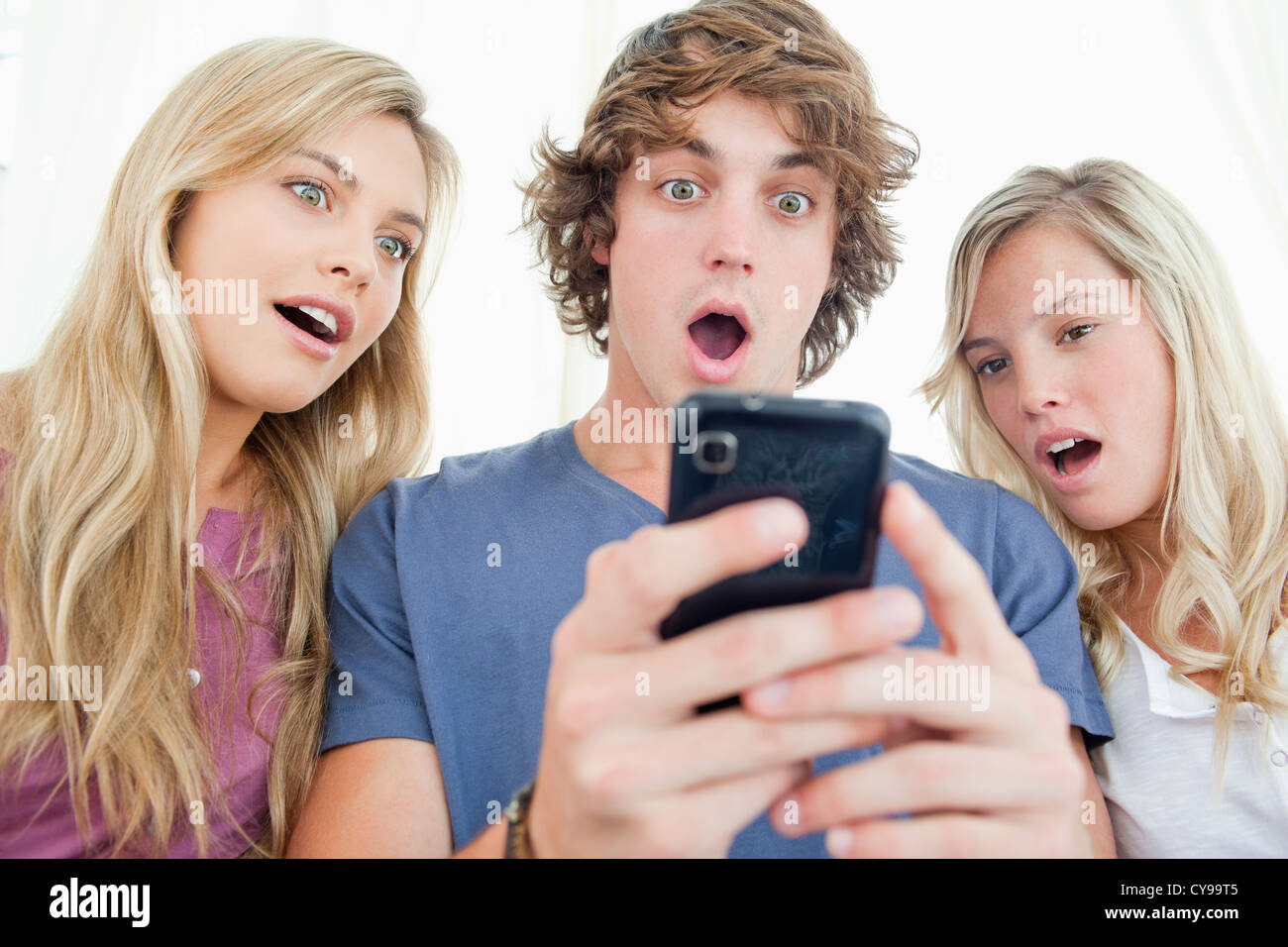 Three friends are surprised at the message on the phone Stock Photo - Alamy
