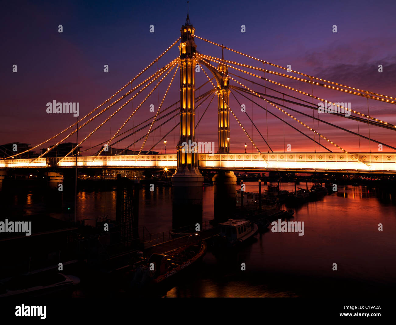 Albert Bridge lit up at night seen from Chelsea Embankment London ...