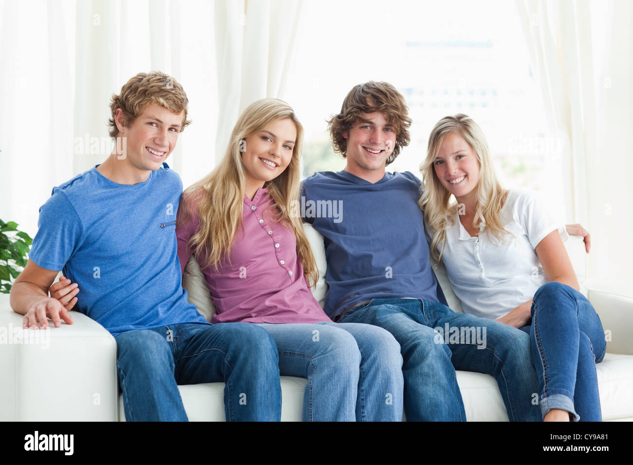 Friends holding each other as they look at the camera Stock Photo - Alamy