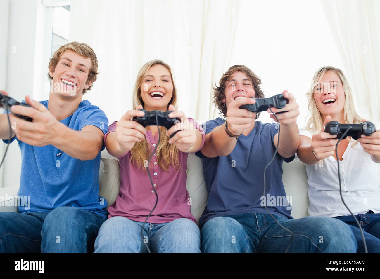 A group of friends all playing video games together and smiling Stock ...