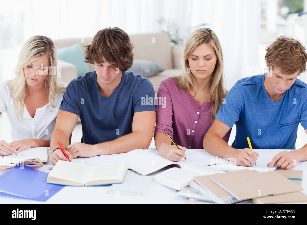 Four students sitting together and studying Stock Photo - Alamy