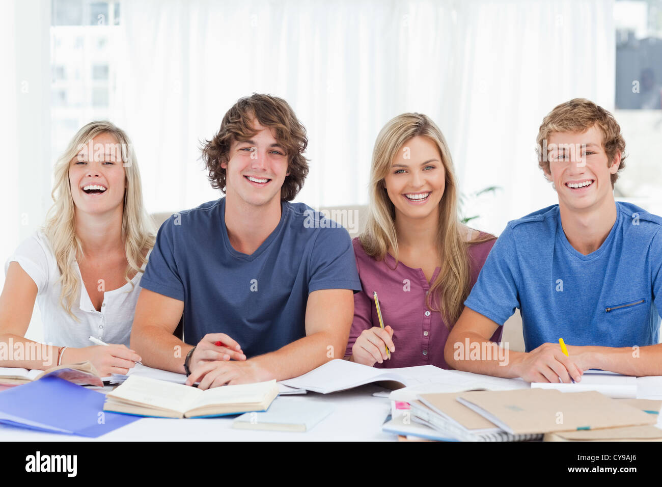 Four smiling students looking into the camera Stock Photo - Alamy