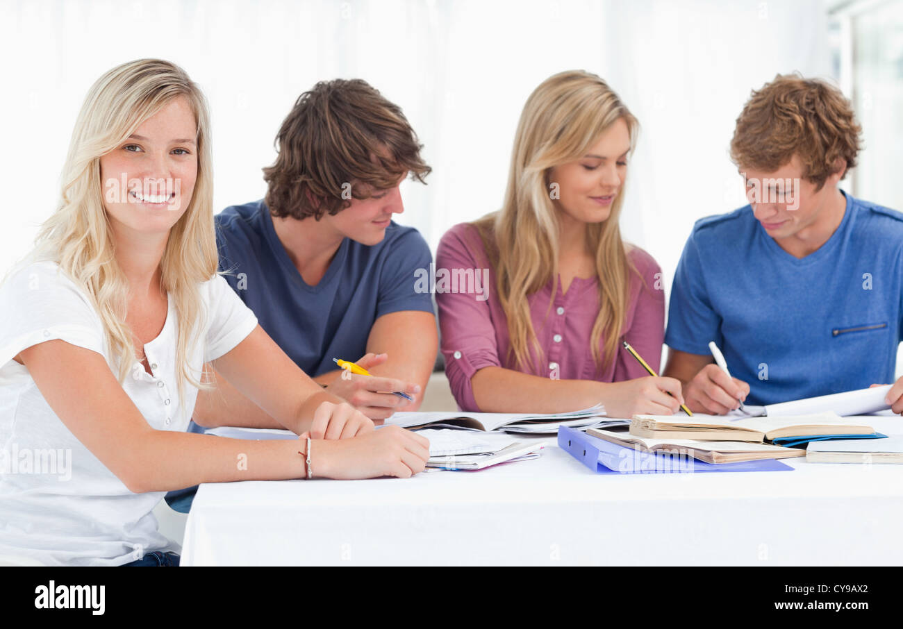A study group working hard as one girl smiles and looks at the camera ...