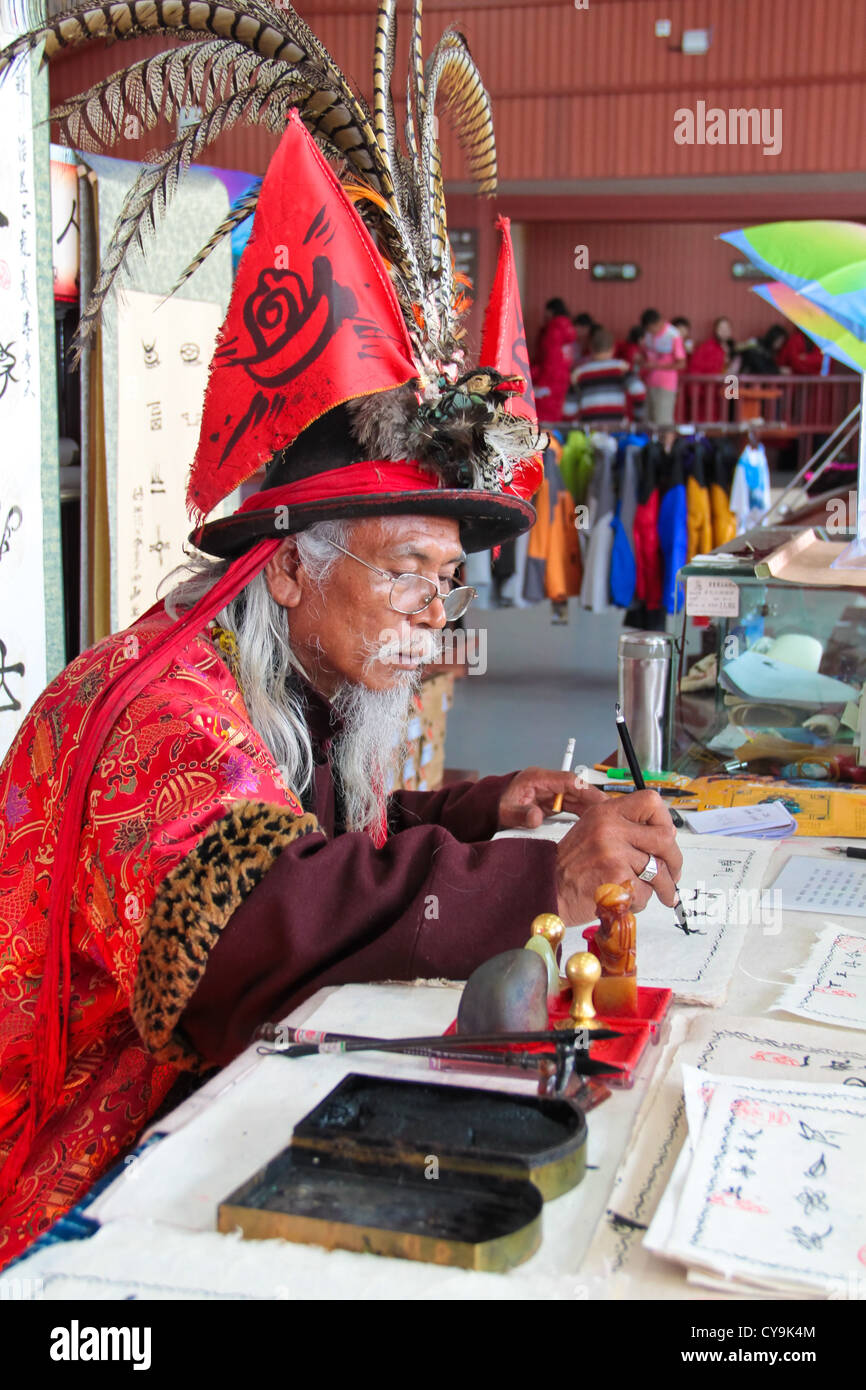 An Elder writing Dongba language characters at the lobby on top the ...