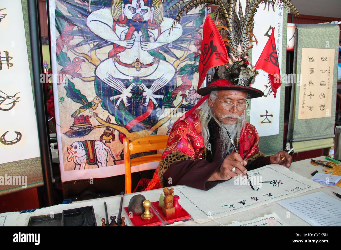 An Elder writing Dongba language characters at the lobby on top the ...