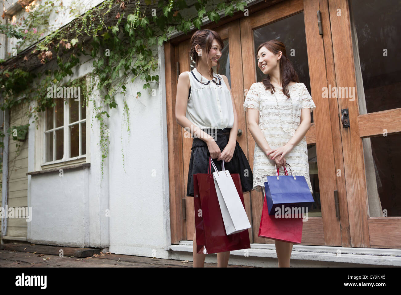 Two Young Women Holding Shopping Bag Stock Photo - Alamy