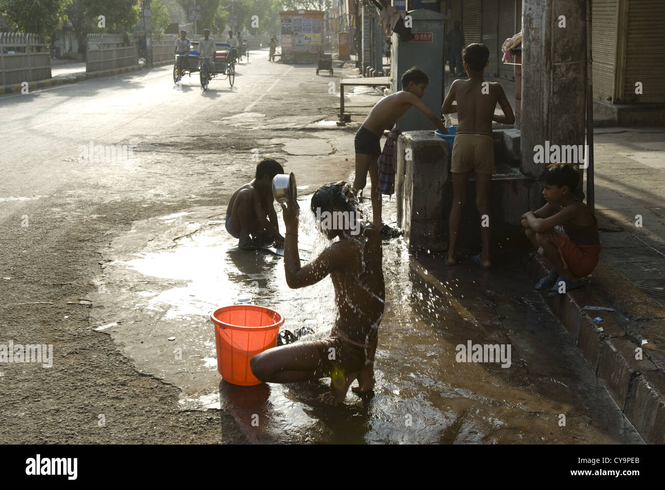 A teenager has an early morning wash on the street in Old Delhi, India ...