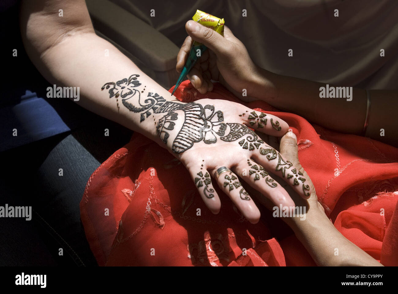 A henna artist decorates the hand of a guest at a pre-wedding 'Mehendi ...