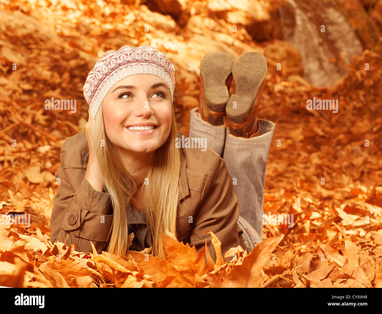 Picture of pretty cheerful woman lay down on the ground covered dry ...