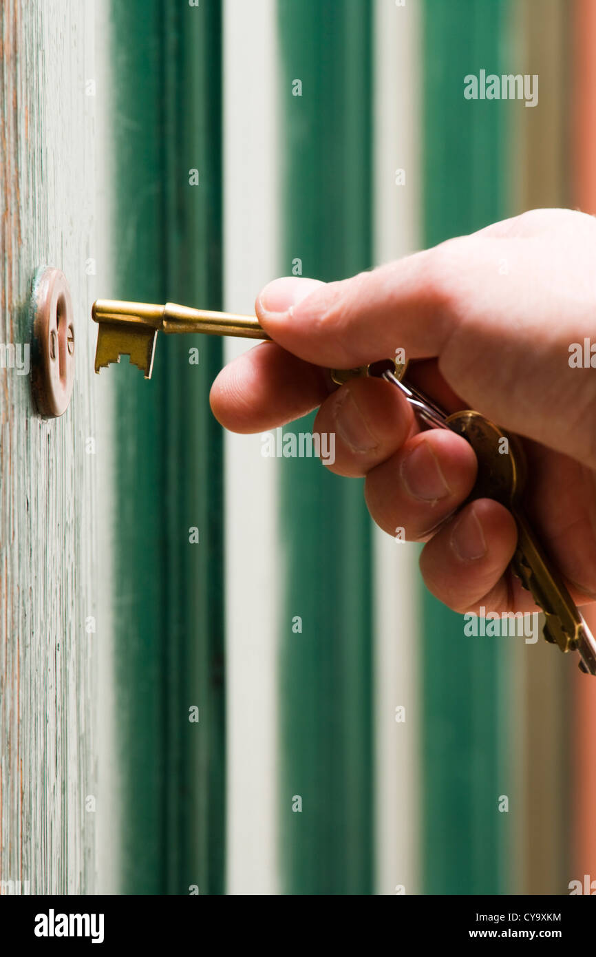 Hand putting key into lock Stock Photo - Alamy