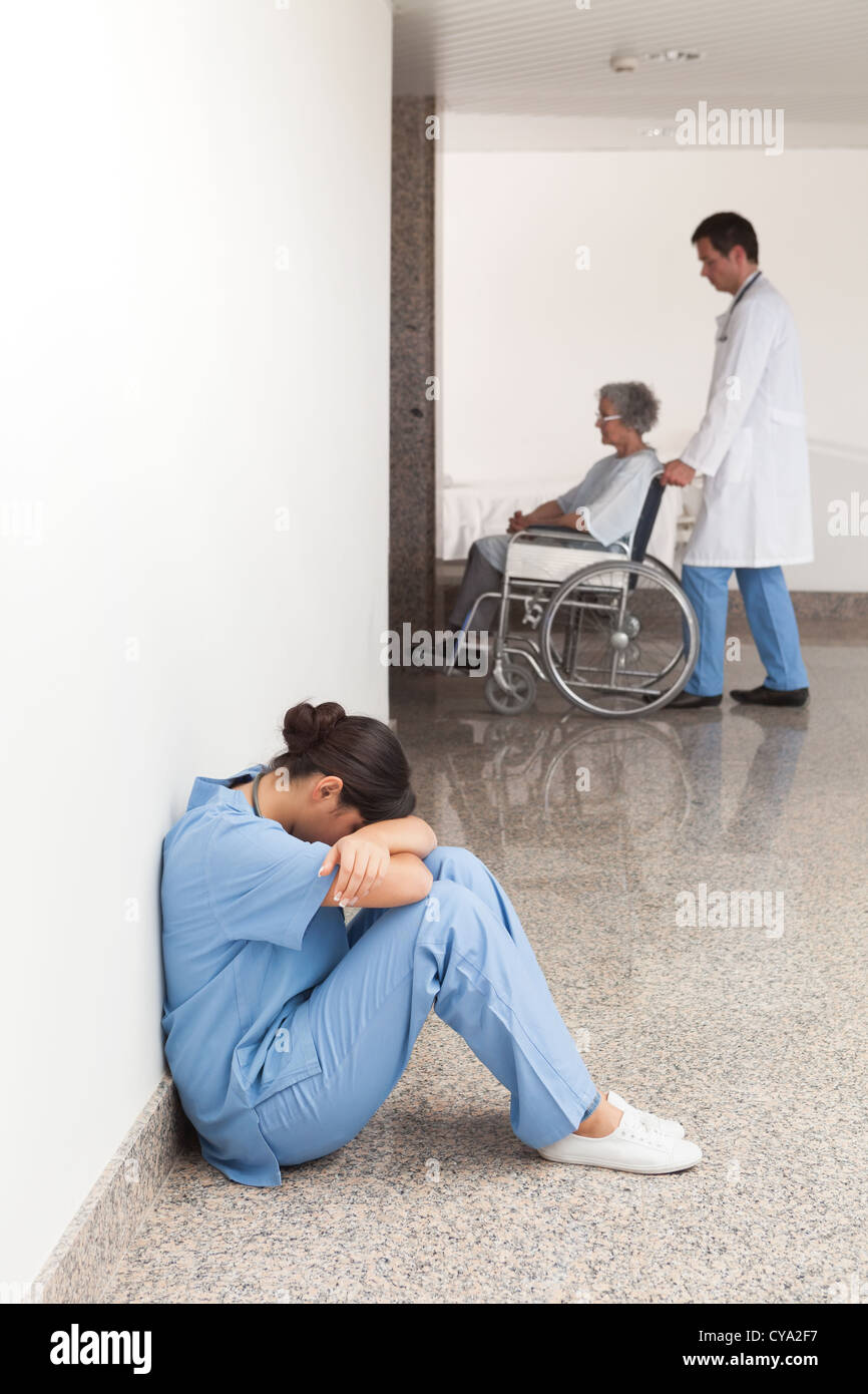 Nurse sitting on the ground with head in hands Stock Photo - Alamy