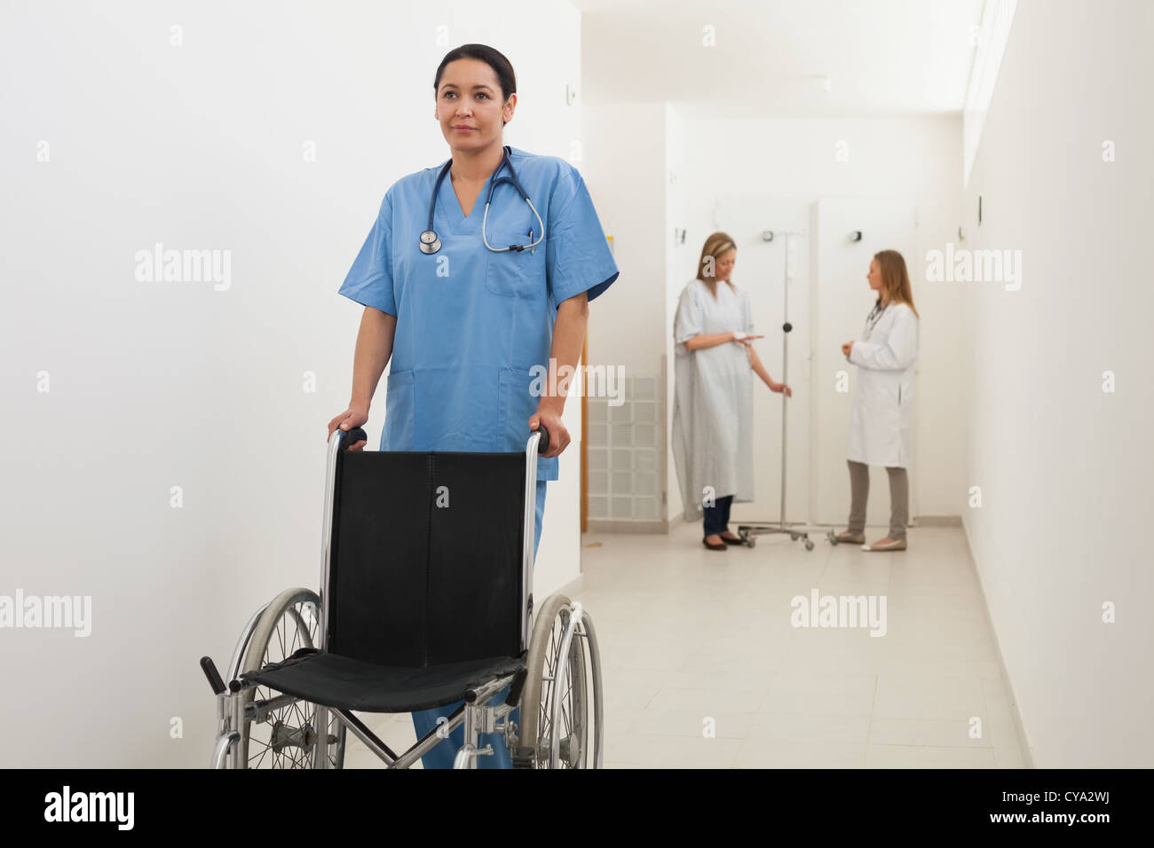 Nurse pushing empty wheelchair Stock Photo - Alamy