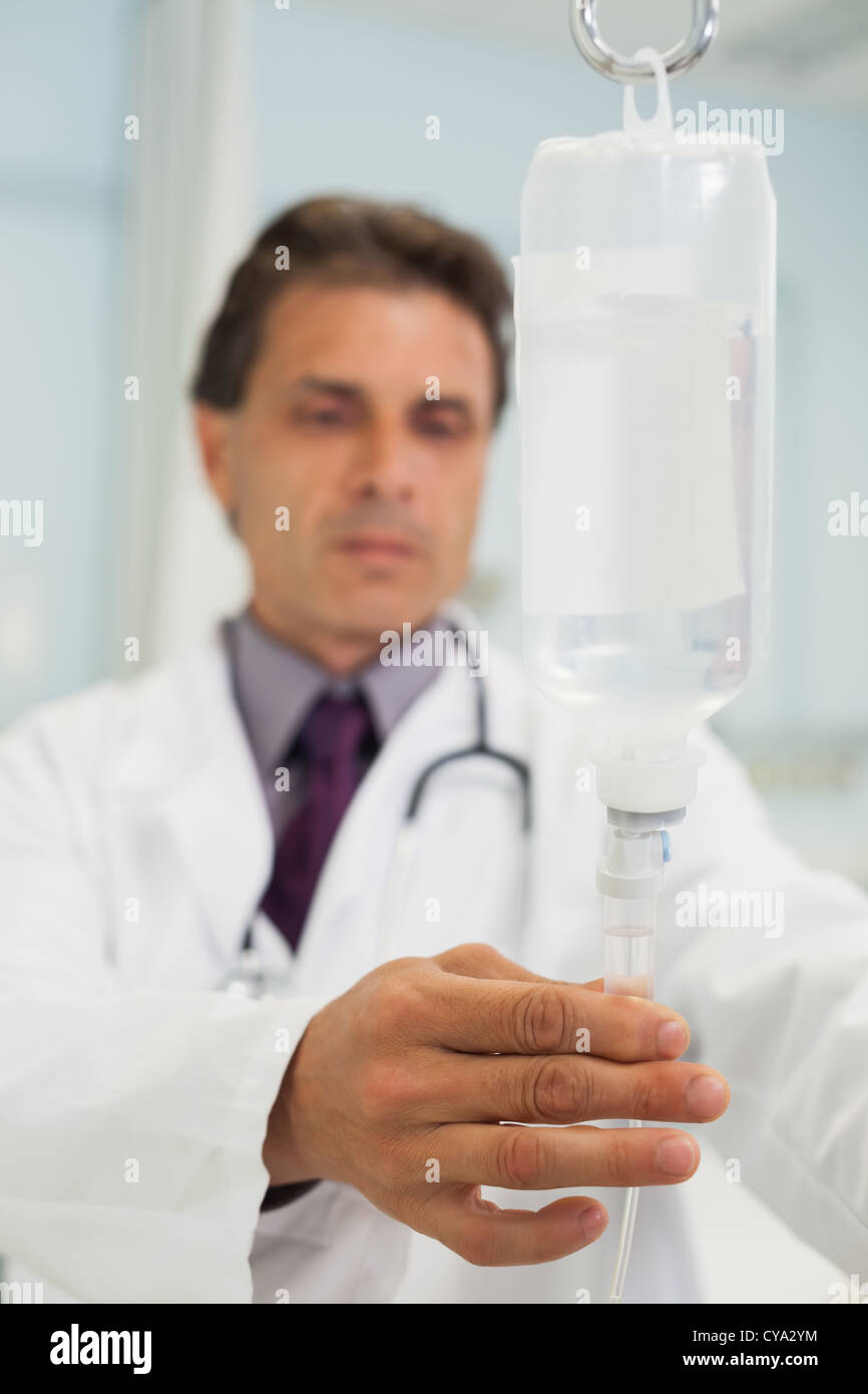 Concentrated doctor connecting the drip Stock Photo - Alamy