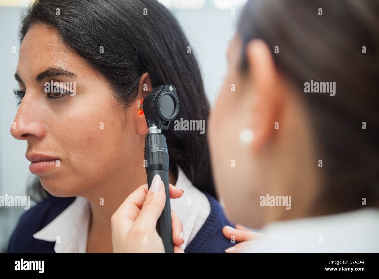 Doctor using otoscope to check woman's ear Stock Photo - Alamy