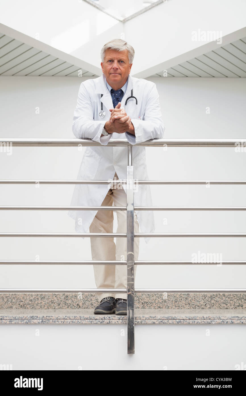 Doctor leaning on rail in hospital corridor Stock Photo - Alamy