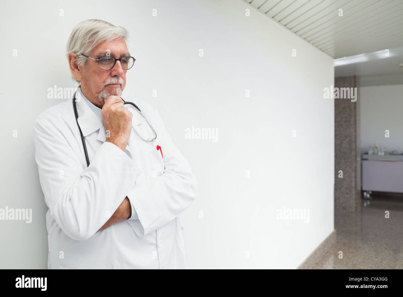 Doctor leaning against wall in corridor and thinking Stock Photo - Alamy