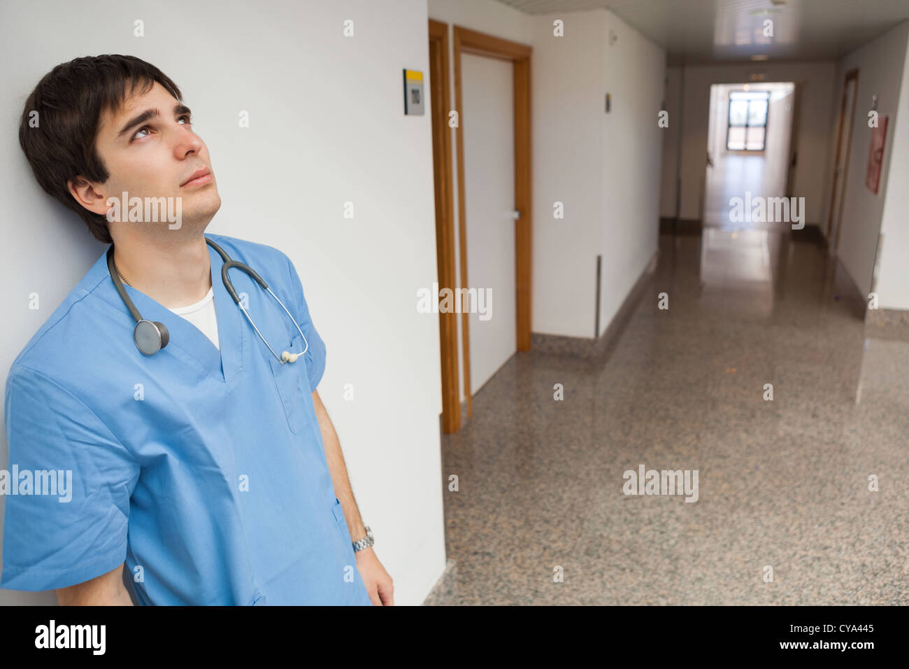 Distressed nurse leaning on wall Stock Photo - Alamy