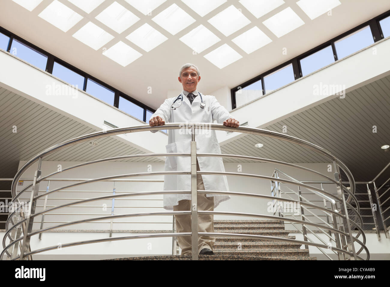 Doctor standing at the railing looking down Stock Photo - Alamy