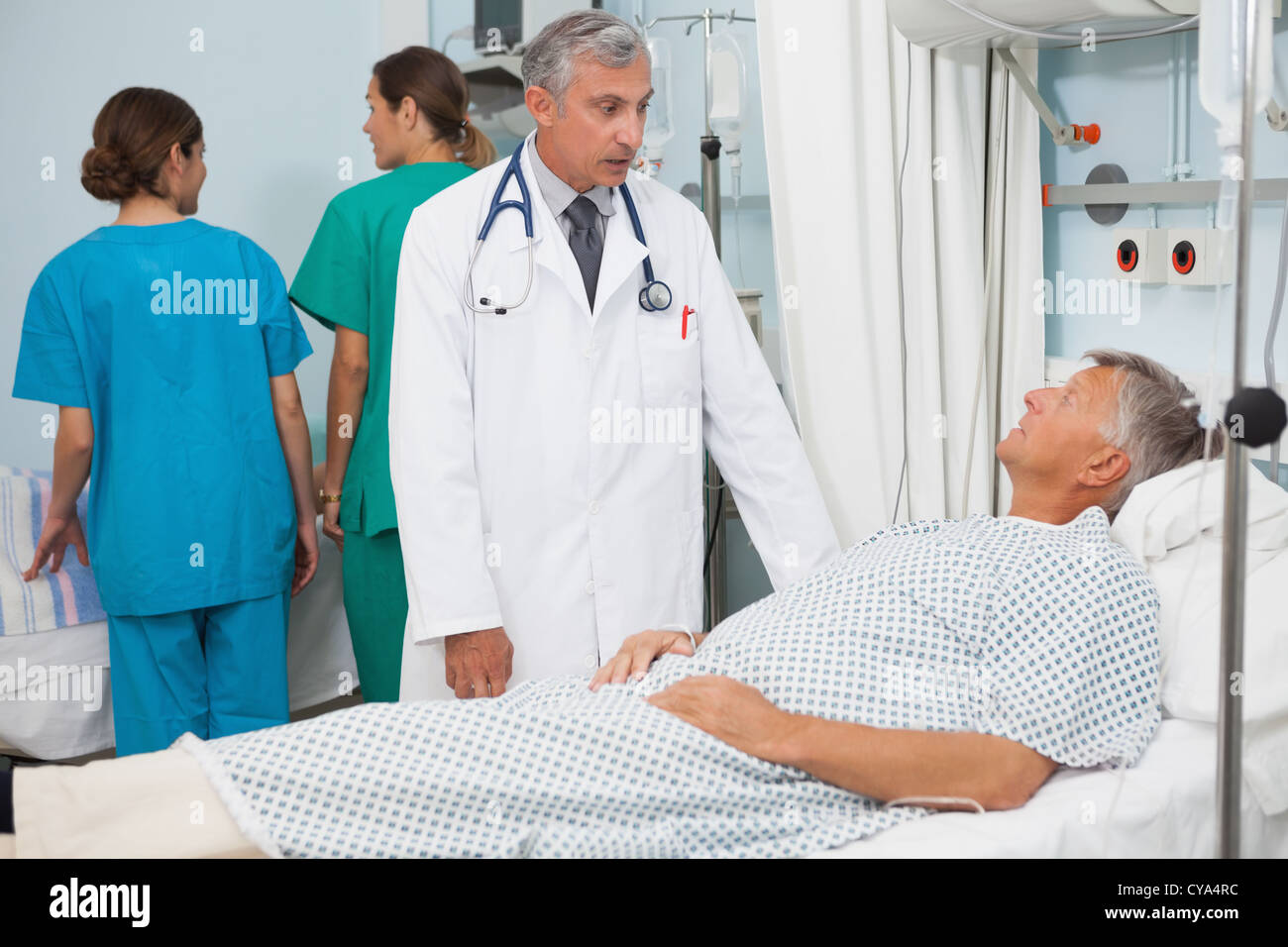 Patient lying in bed talking to doctor Stock Photo - Alamy
