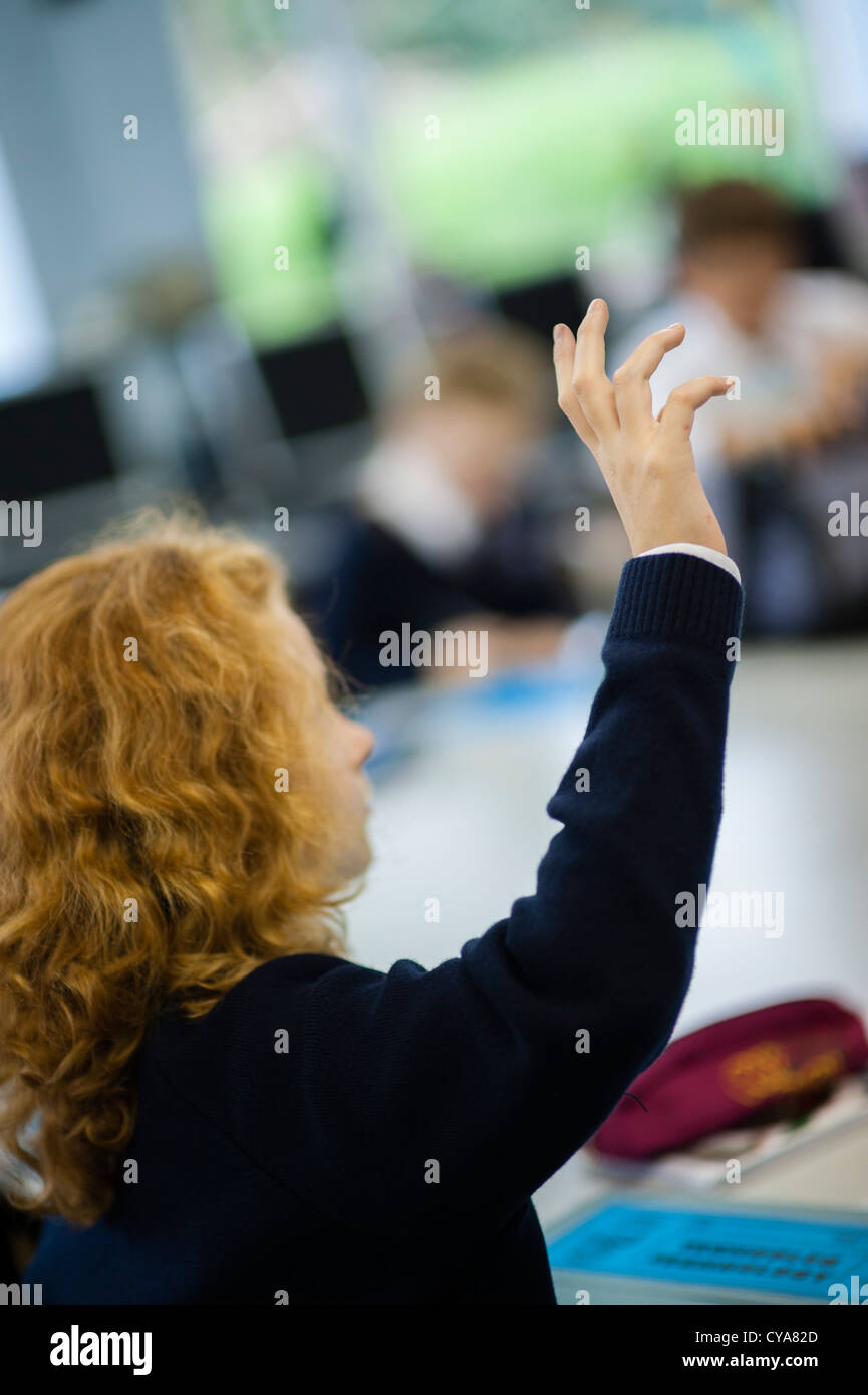 Pupil holding up hand to answer question in class at a secondary ...