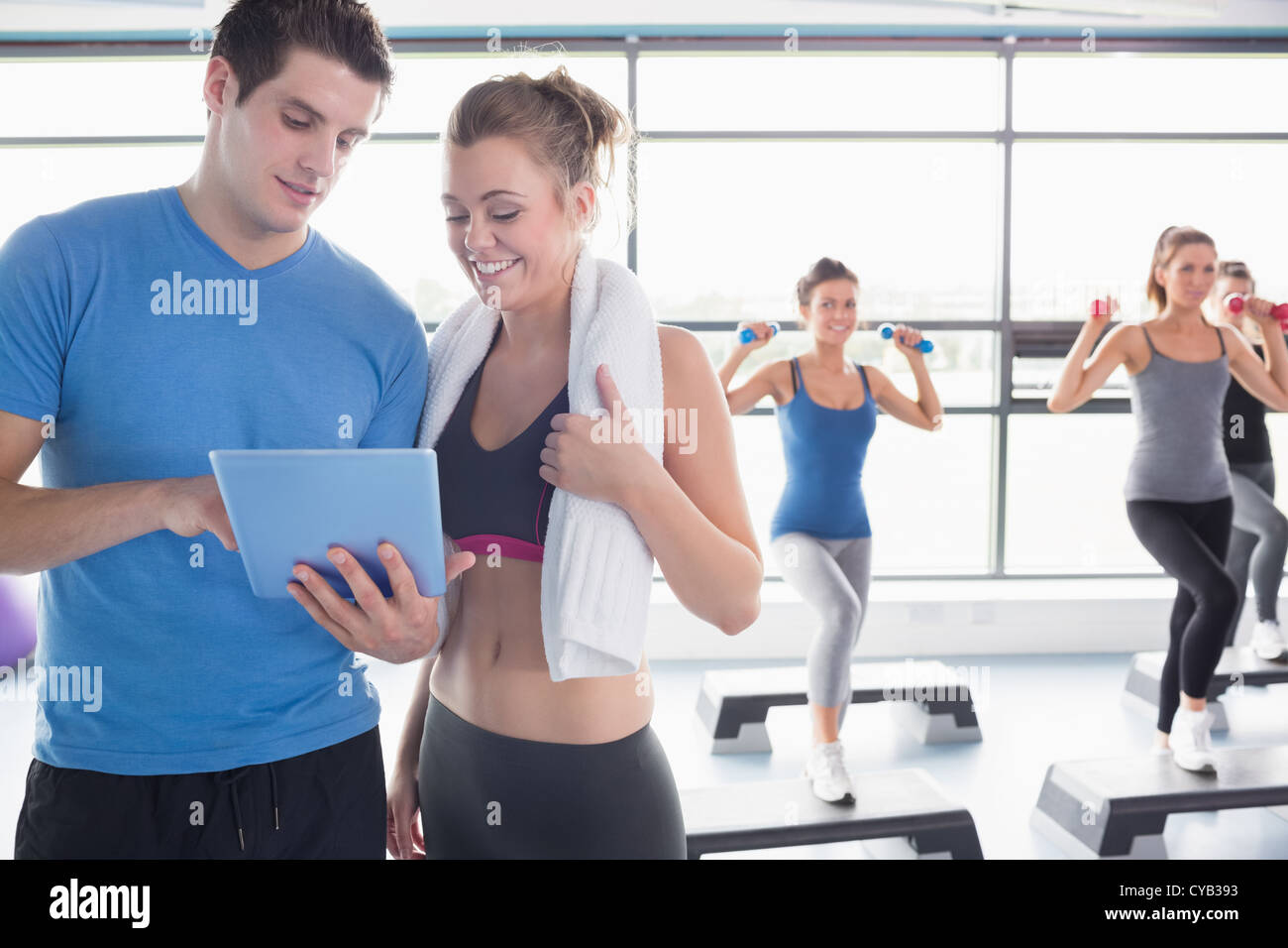 Trainer and woman talking while aerobics class lifting weights Stock ...