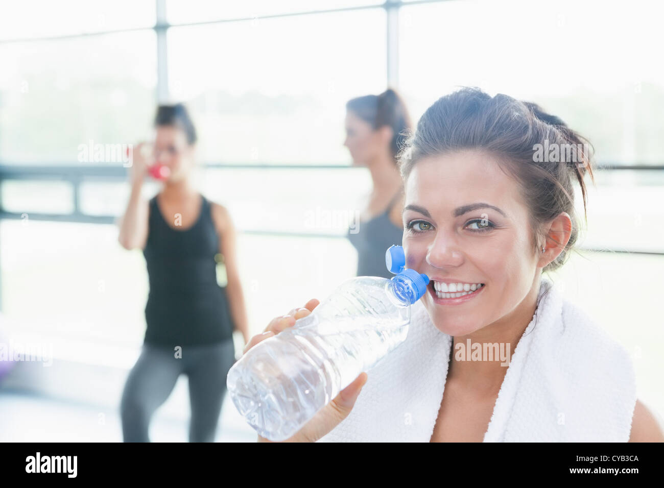 Women talking while another drinking water in fitness studio Stock ...