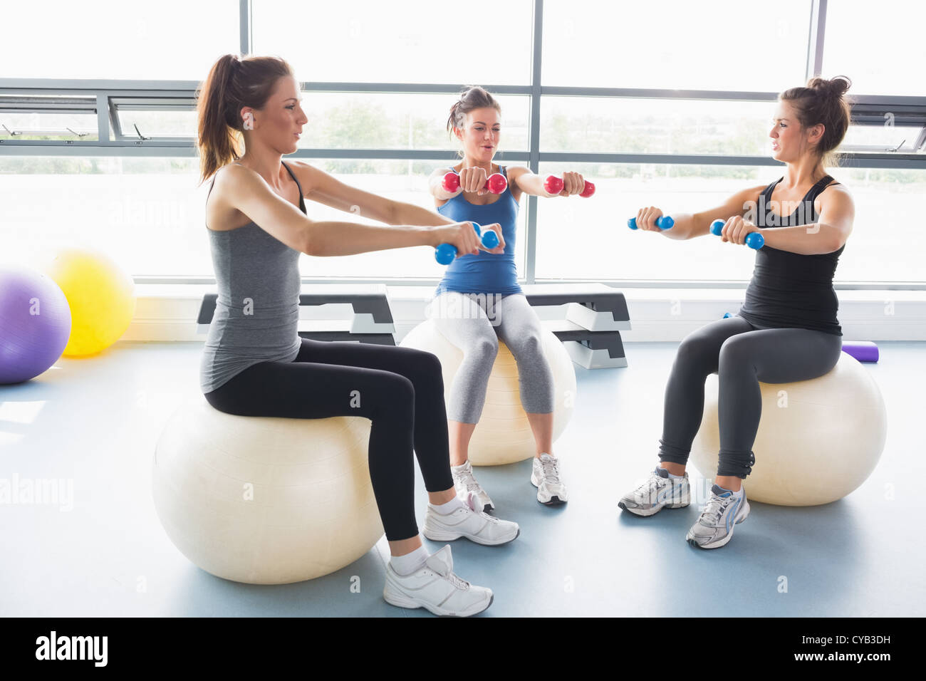 Three women lifting weights together on exercise balls Stock Photo - Alamy