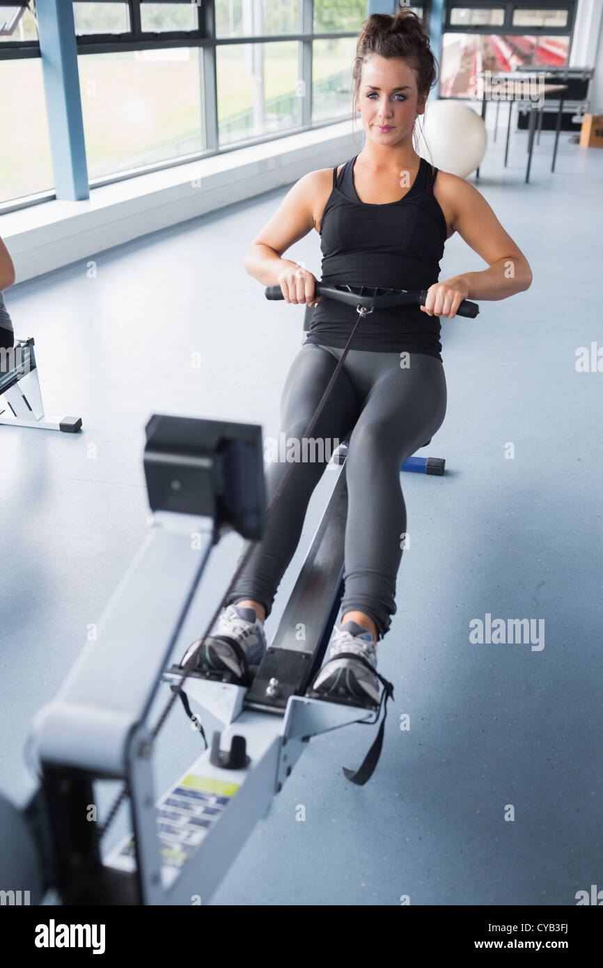 Woman training hard on row machine Stock Photo - Alamy