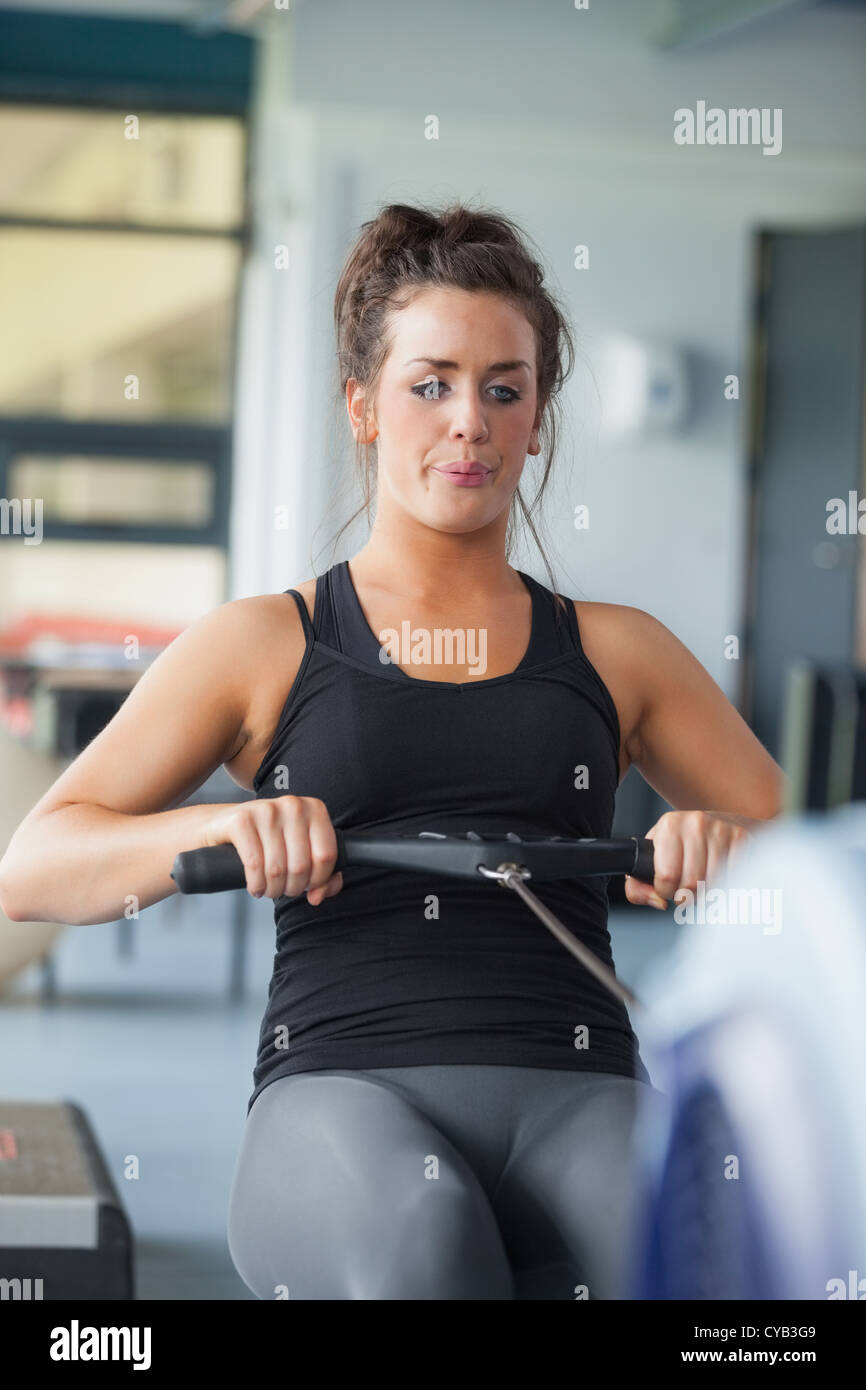 Woman training hard on row machine Stock Photo - Alamy