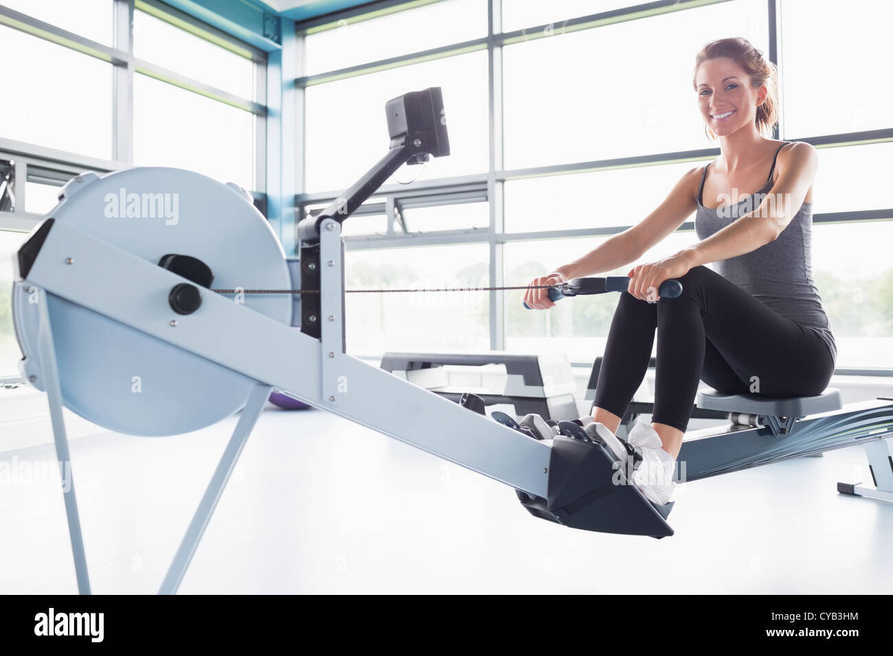 Woman training happily on row machine Stock Photo - Alamy