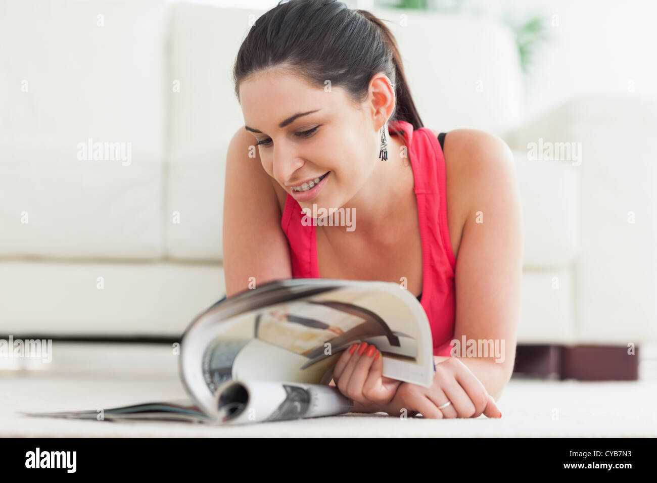 Woman lying on floor looking at magazine Stock Photo - Alamy
