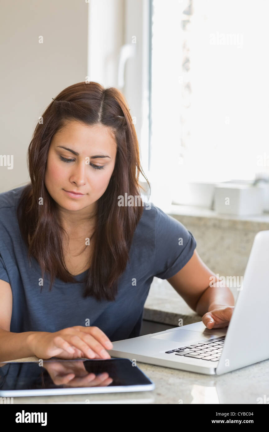 Brunette typing on the tablet pc and laptop Stock Photo - Alamy