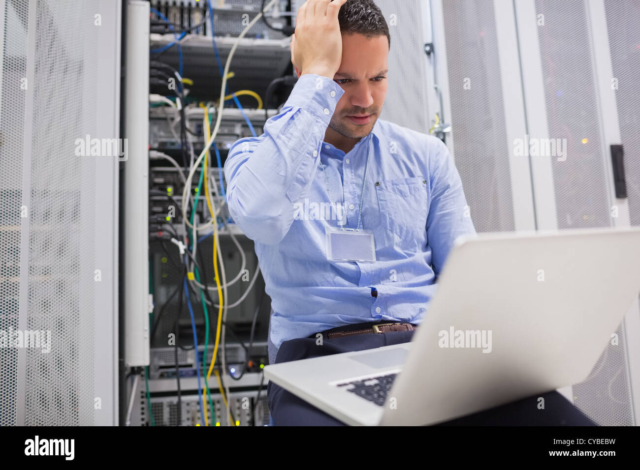 Man getting stressed with laptop over servers Stock Photo - Alamy