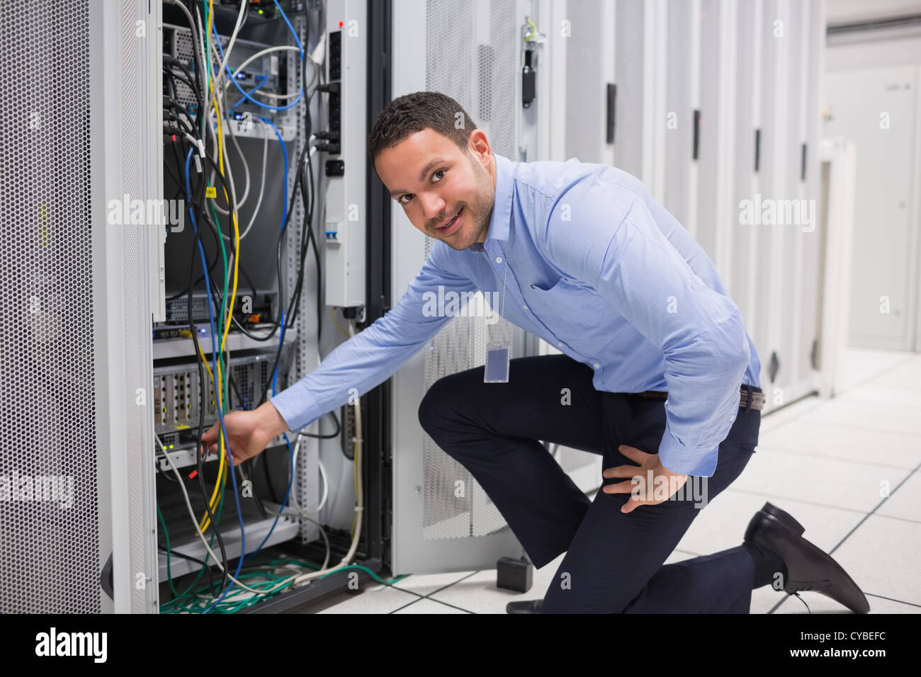 Technician plugging cable into server Stock Photo - Alamy