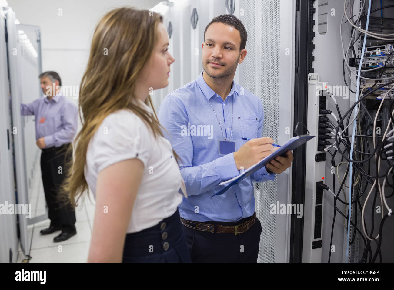 Two people checking servers with one holding clipboard Stock Photo - Alamy