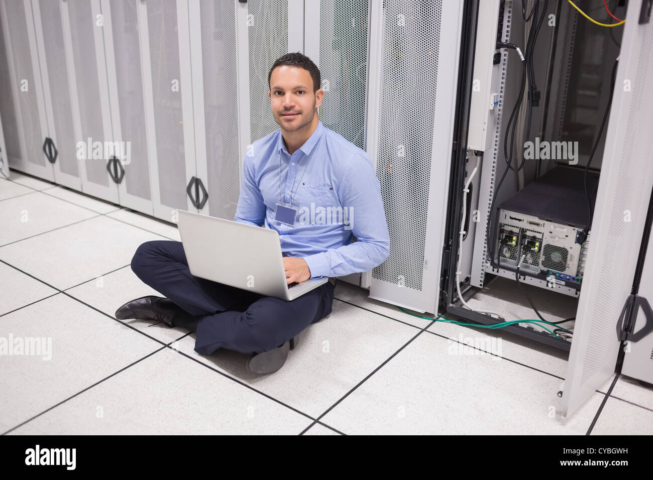 Man sitting beside servers with laptop Stock Photo - Alamy