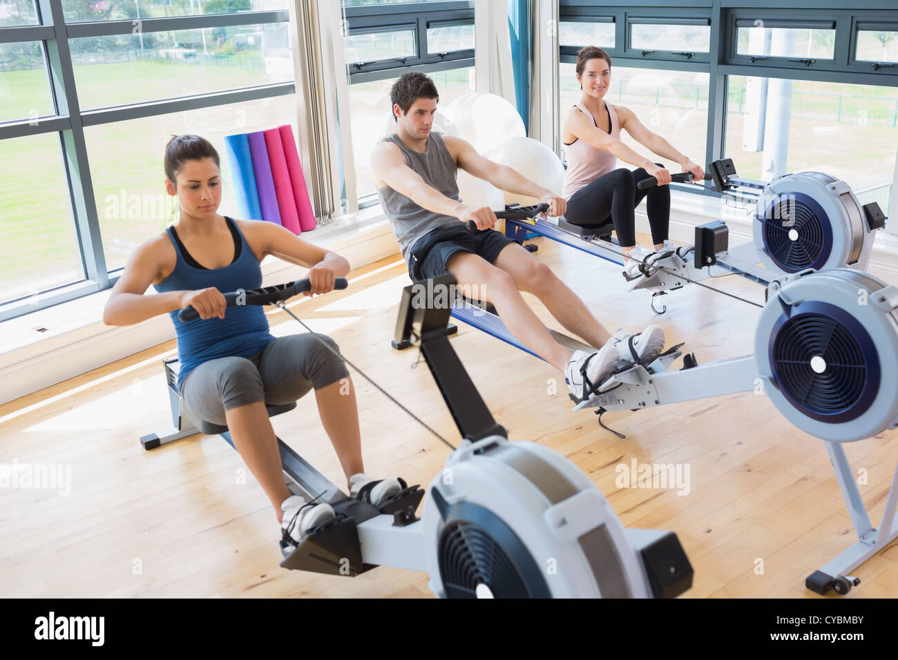 Three people on rowing machines Stock Photo - Alamy