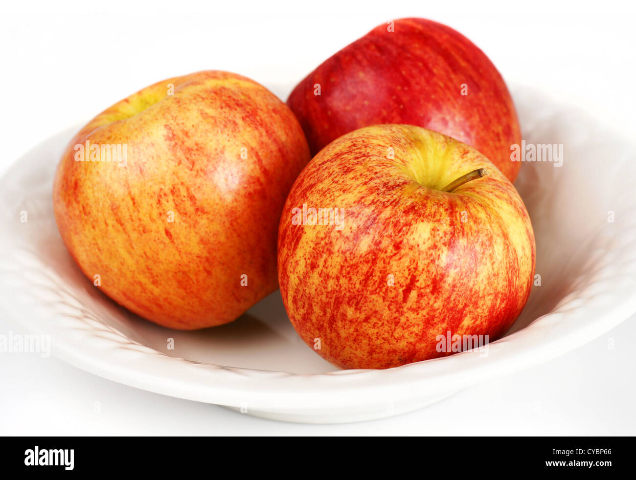 Clean and simple still life with three gala apples in a white porcelain ...