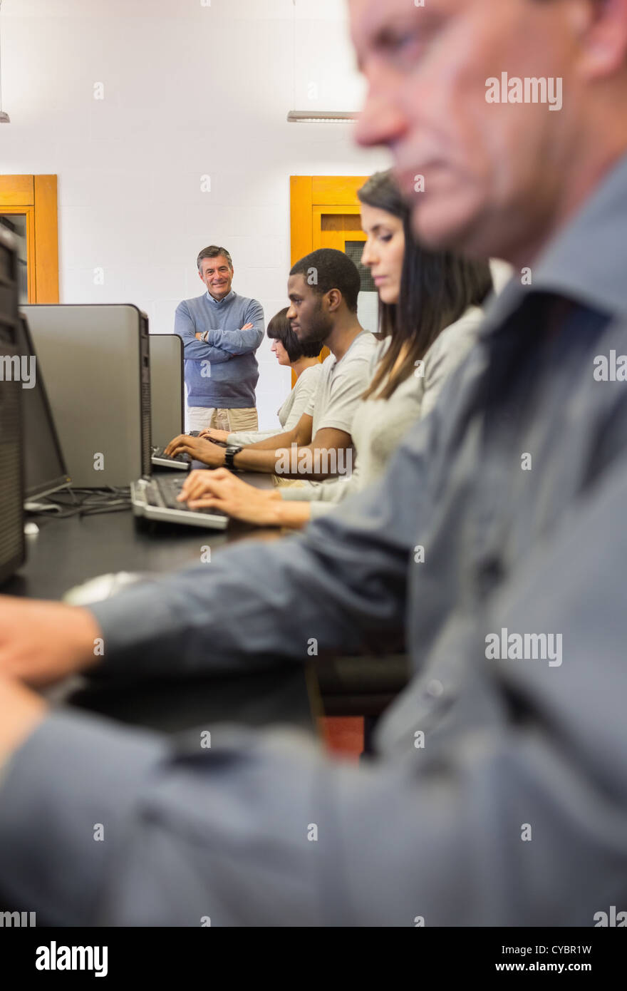 Teacher standing and smiling in computer class Stock Photo - Alamy