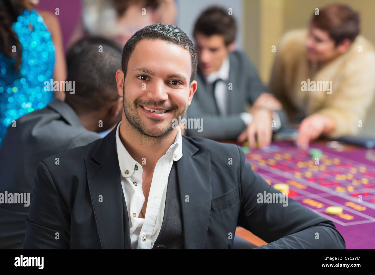 Smiling man sitting leaning on roulette table Stock Photo - Alamy