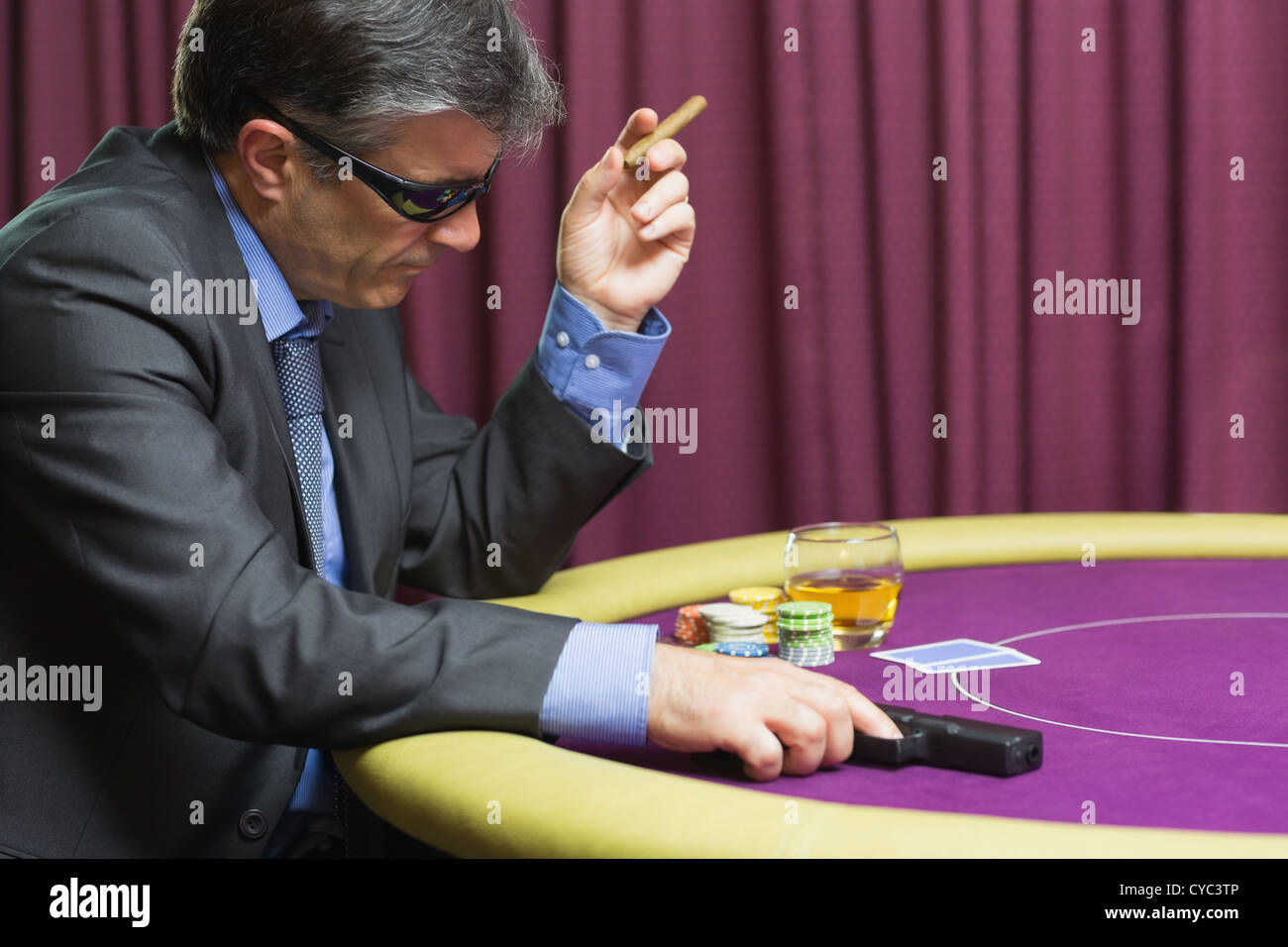 Man with gun sitting at poker table Stock Photo - Alamy