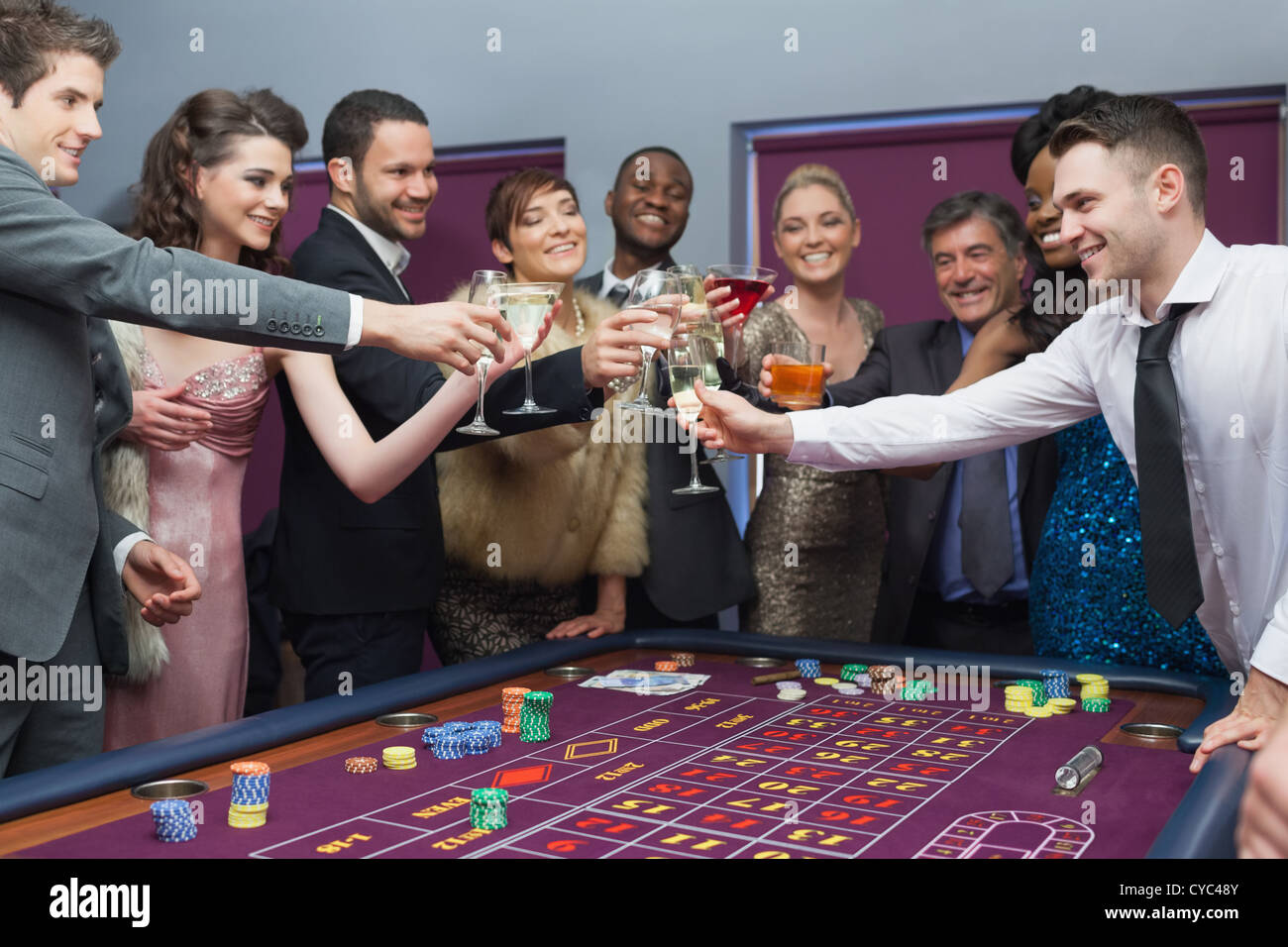 People standing clinking glasses at roulette table Stock Photo - Alamy